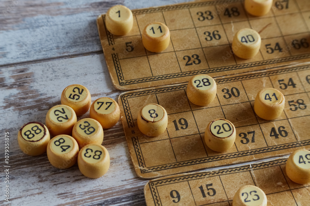Tokens from a bingo bag cover the numbers on old yellowed vintage cards ...