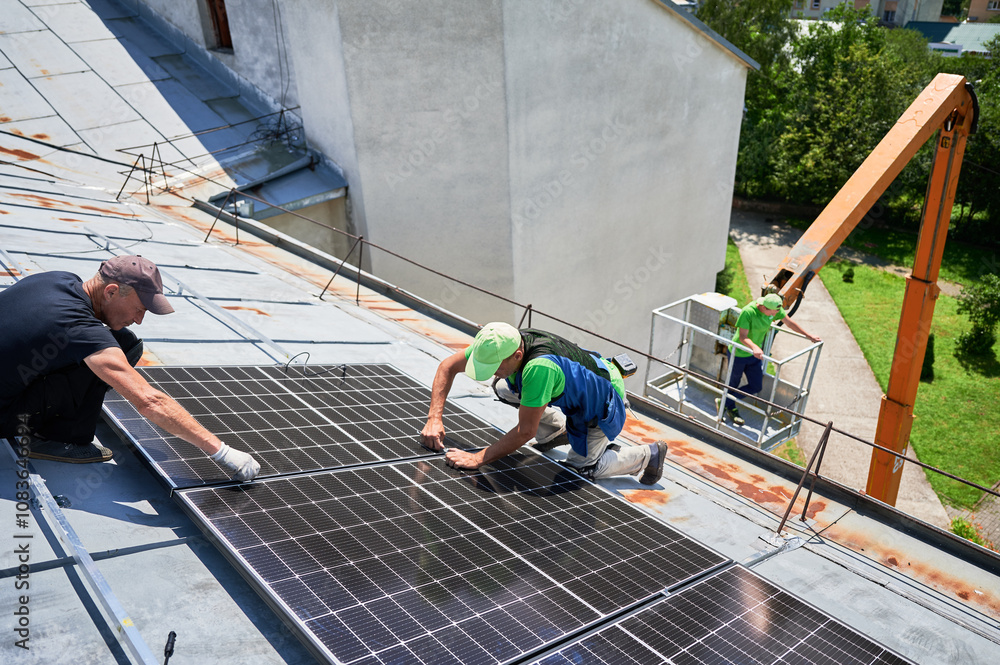 Workers building solar panel system on metal rooftop of house with ...