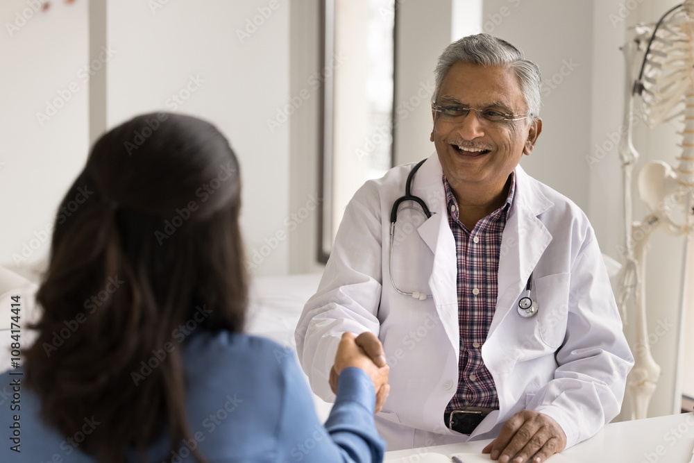 Male doctor and female patient sit at desk in clinic office and shaking ...