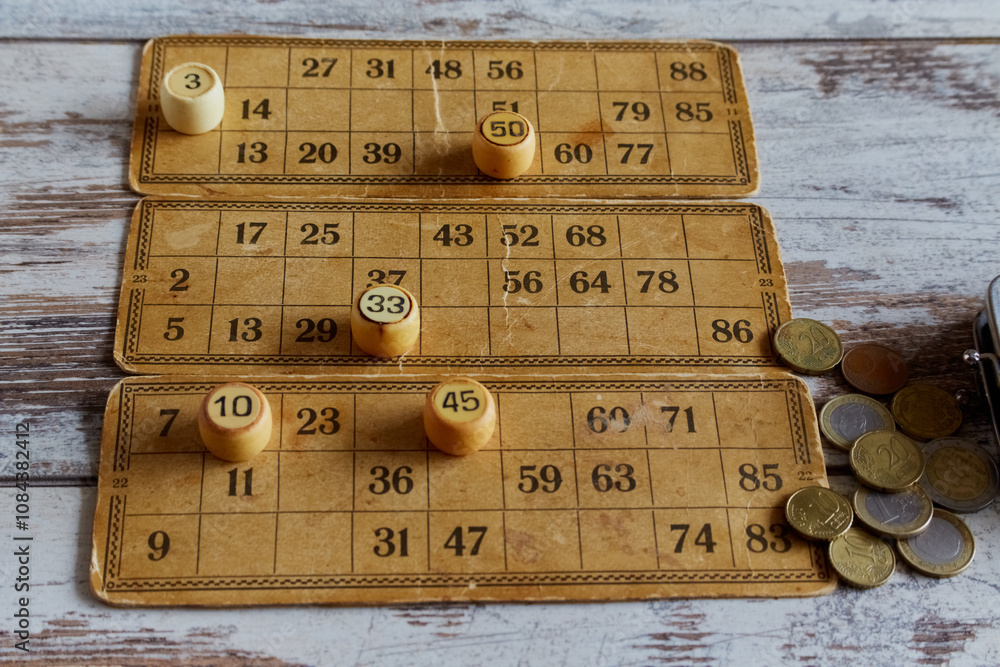 Yellowed vintage bingo cards on a wooden table with euro cent coins ...