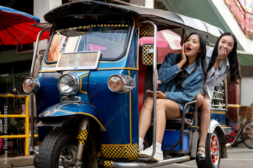 Two excited Asian girls enjoy a ride in a tuk-tuk in Thailand, amazed ...