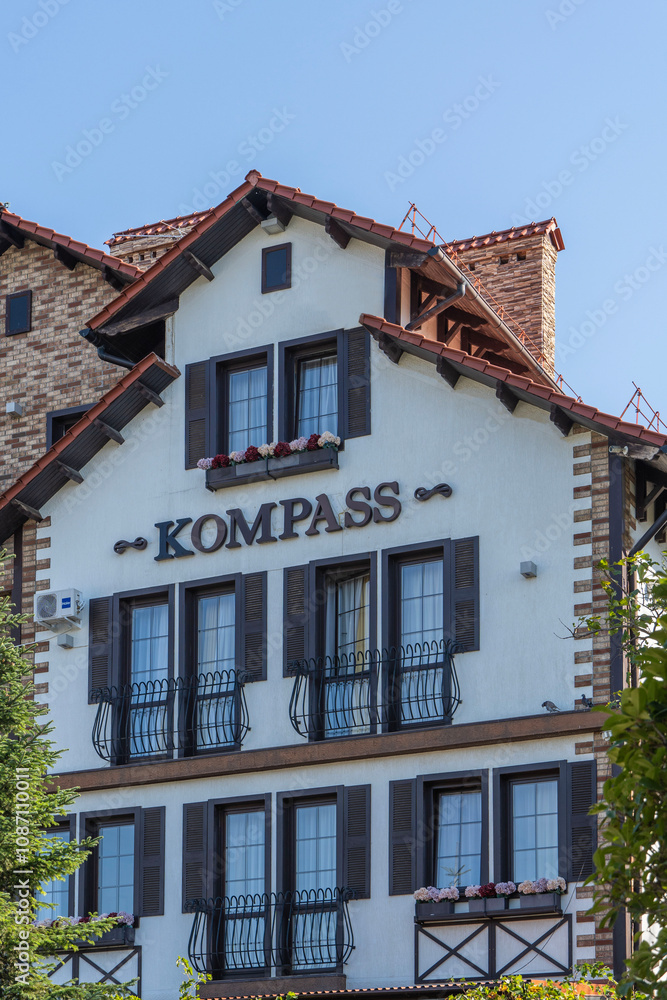 Facade of Compass Hotel with shutters on windows and tiled roof. Black ...
