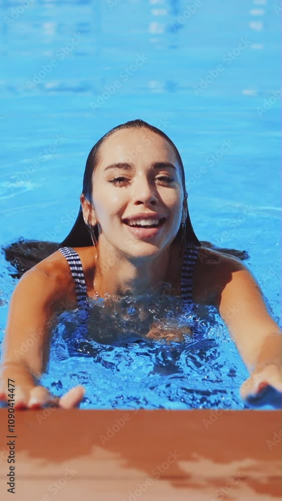 Woman with bright smile emerges from pool, water glistening on her skin ...