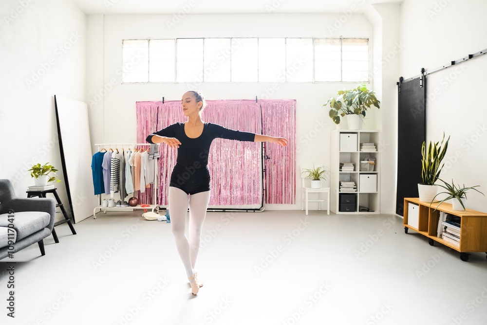 A ballet dancer stands in a mid-practice pose in a spacious, light ...