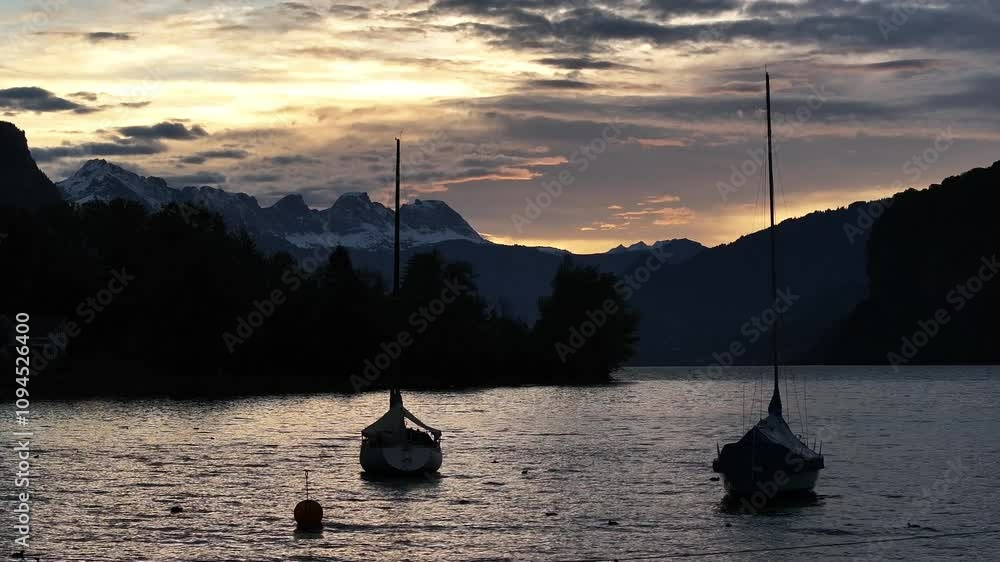 Boats on Lake Walensee moored in the village of Weesen. Silhouettes of ...