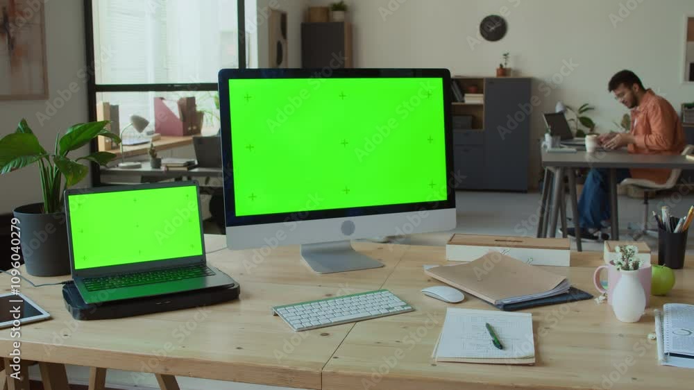 Medium full arc shot of desktop computer and laptop with plain green ...