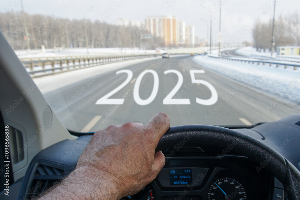 The driver holds his hand on the steering wheel of the car, which is ...