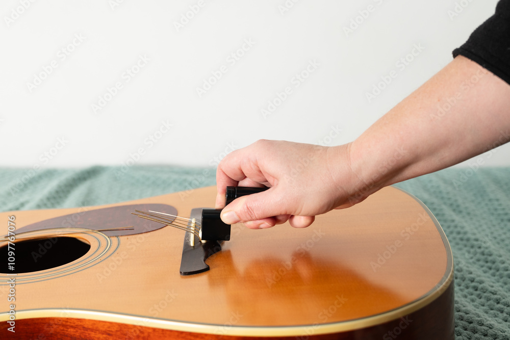 Photo & Art Print removing pegs or pins from guitar bridge with a ...