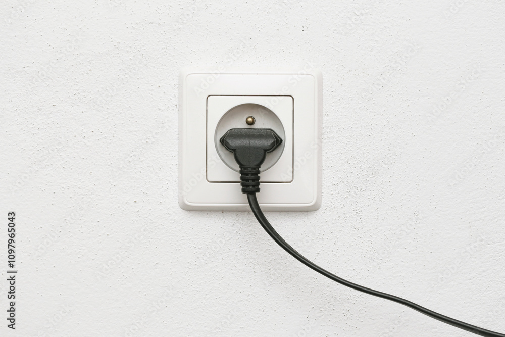 Electrical socket isolated on white wall. Black wire plug plugged in ...