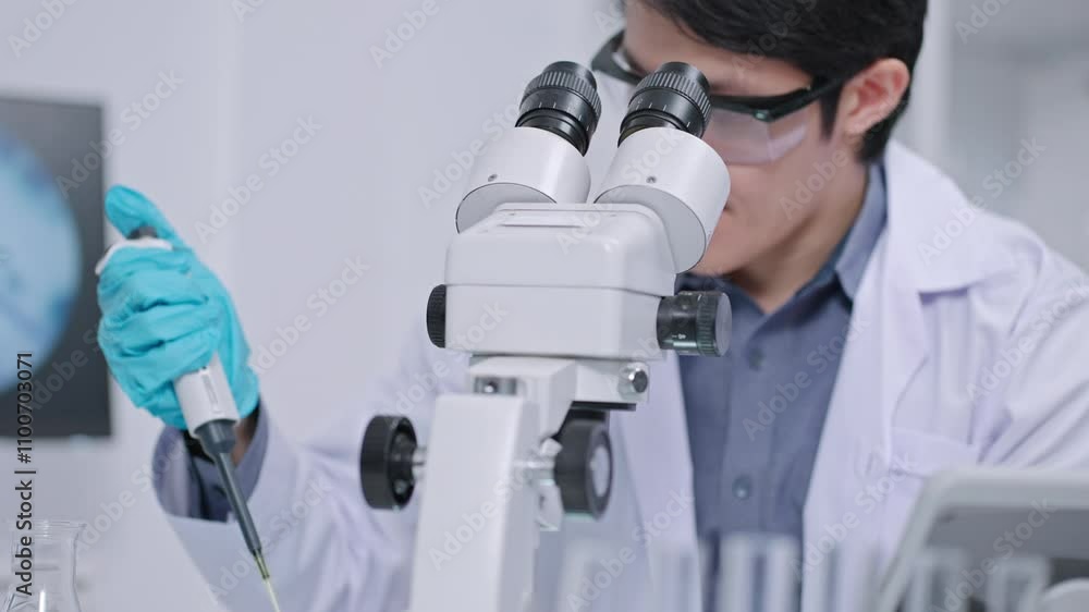 young male scientist using a microscope.people working at laboratory ...