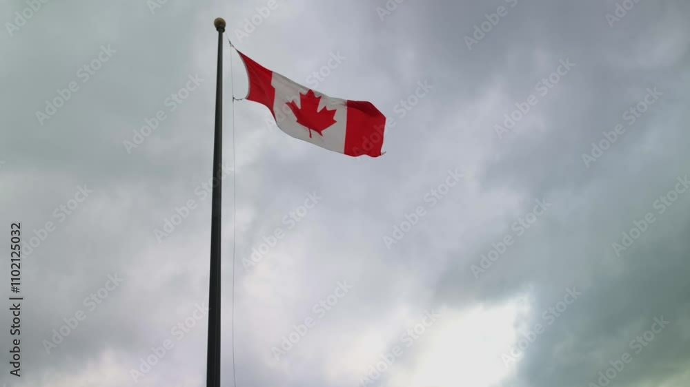 vibrant Canadian flag flutters on tall flagpole set against dramatic ...