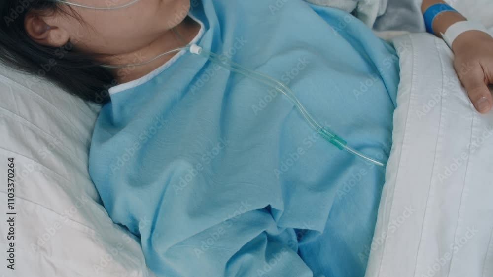 Tilt shot of sleeping Caucasian girl with nasal cannula lying in ...