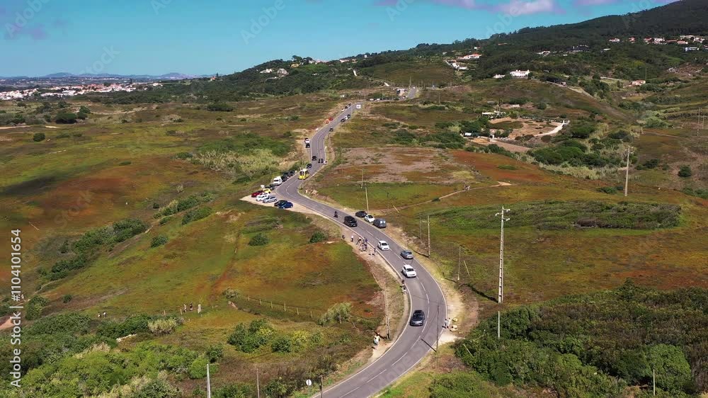 Drone view of a winding two-lane road with moving cars and parked ...