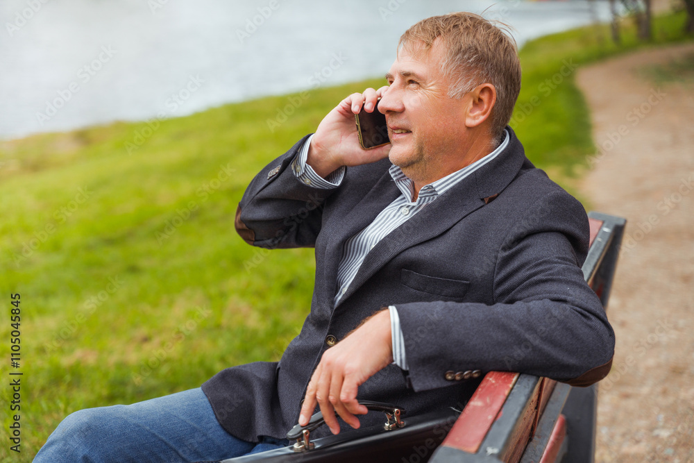 Man in a blazer enjoying a friendly phone call while sitting by a ...