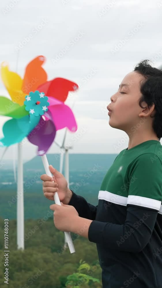 Progressive young asian boy playing with wind turbine toy in the wind ...