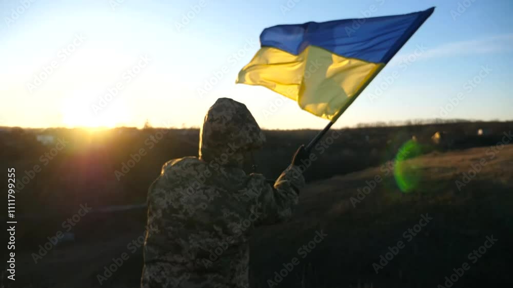 Soldier of ukrainian army stands at hill and holds waving flag of ...