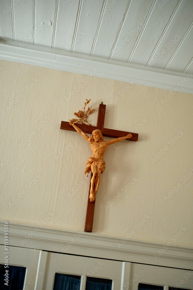 Wooden crucifix with a figure of Jesus mounted on a white wall under a ...