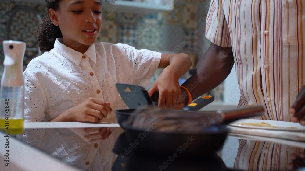 African American father man hand frying pancakes together with daughter ...
