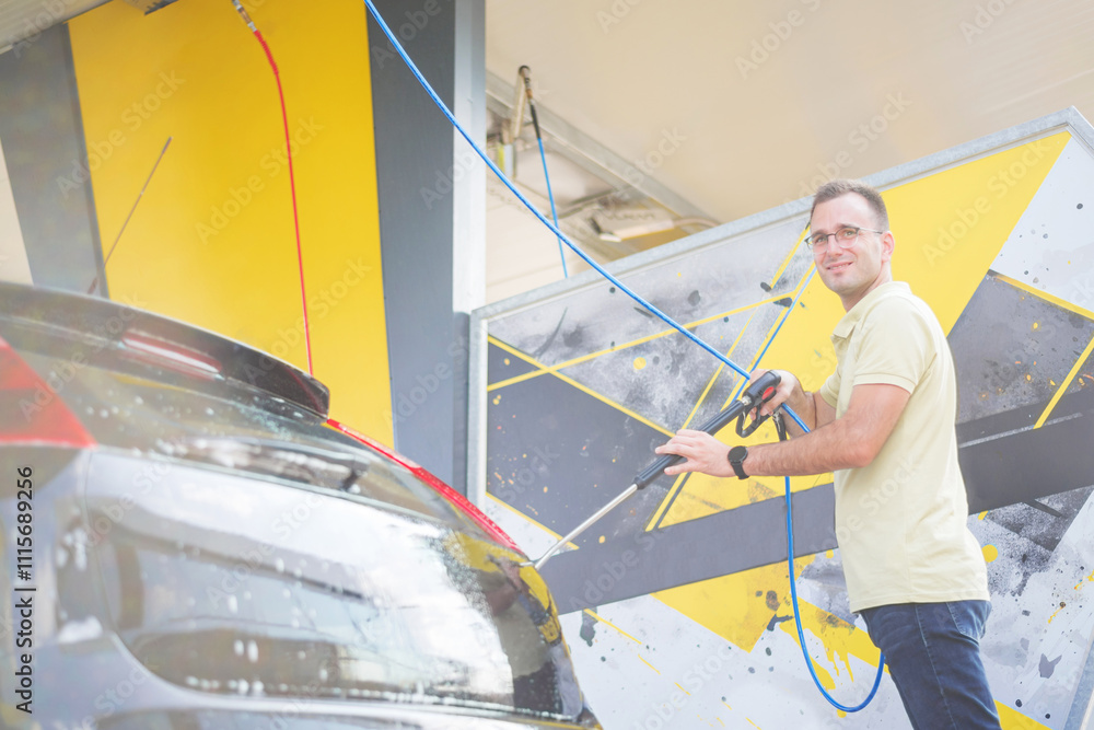 Man washing his car with high pressure washer at self-service car wash ...