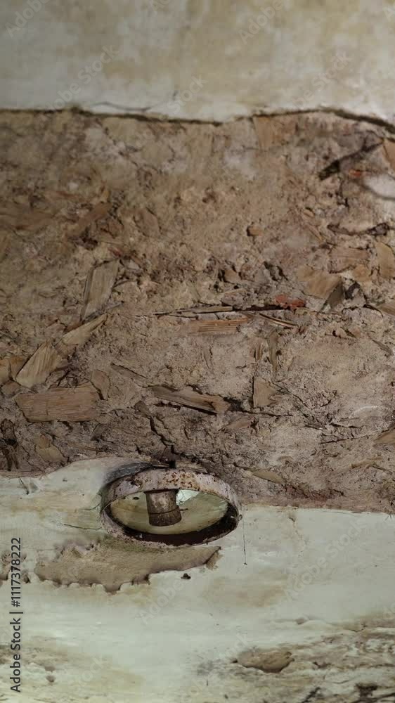 Vertical video. Aged ceiling with visible cracks and a metal light ...