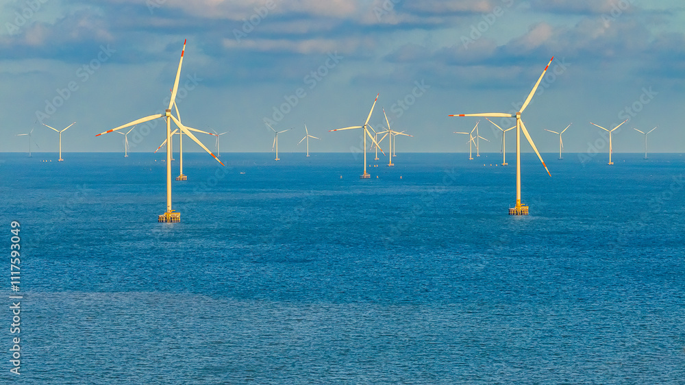Tall windmill turbines against a clear blue sky, generating renewable ...