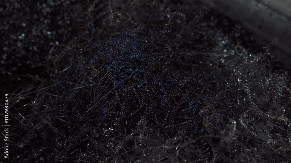 Close-up footage of metal shavings falling from a lathe machine into a ...