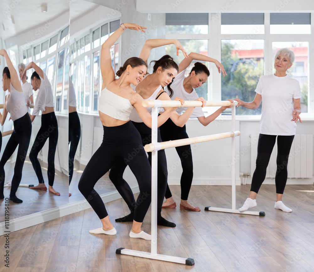 Fit young woman practicing classic ballet moves during group class ...