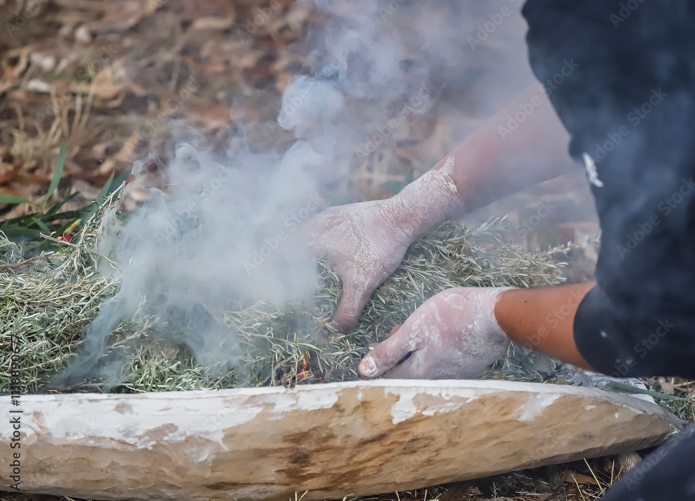 Human hands with green branches, wooden ritual dish and fire ...
