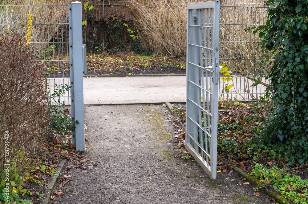 Open metal gate allowing access to paved area in a park Stock Photo ...
