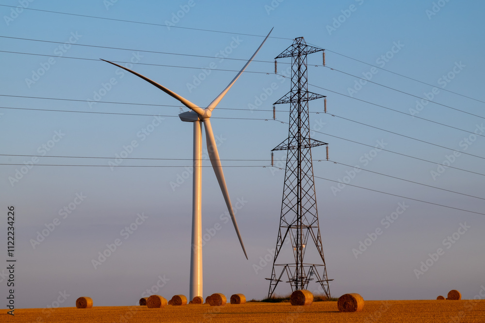 Electricity pylon and wind turbine in straw bale field Stock Photo ...