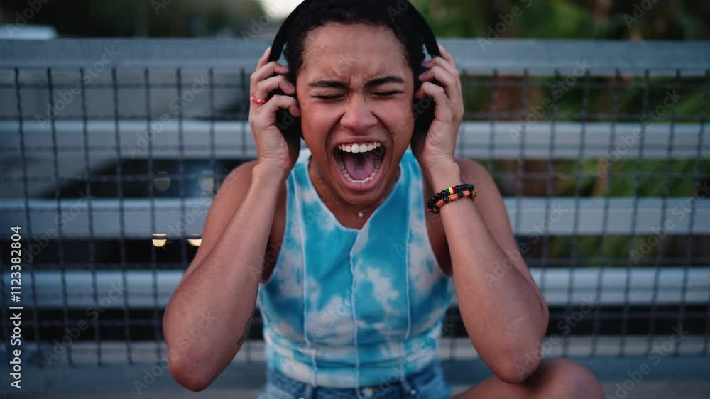 dark-skinned African American woman crying clutches her headphones ...