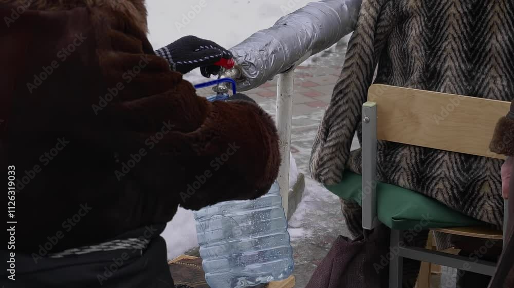 Female nun pours holy water from temple pipe into plastic bottle ...