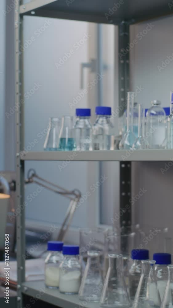 Vertical shot Female chemist in white coat takes test tubes for ...
