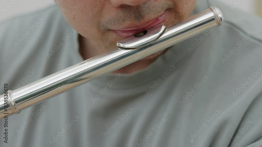 Focused close-up of a musician mouth and lip playing a silver flute ...