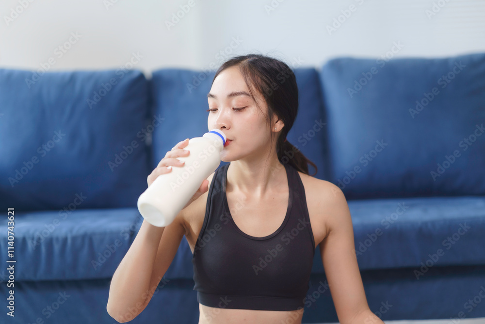 Young asian sportswoman enjoying a refreshing drink of milk from a ...