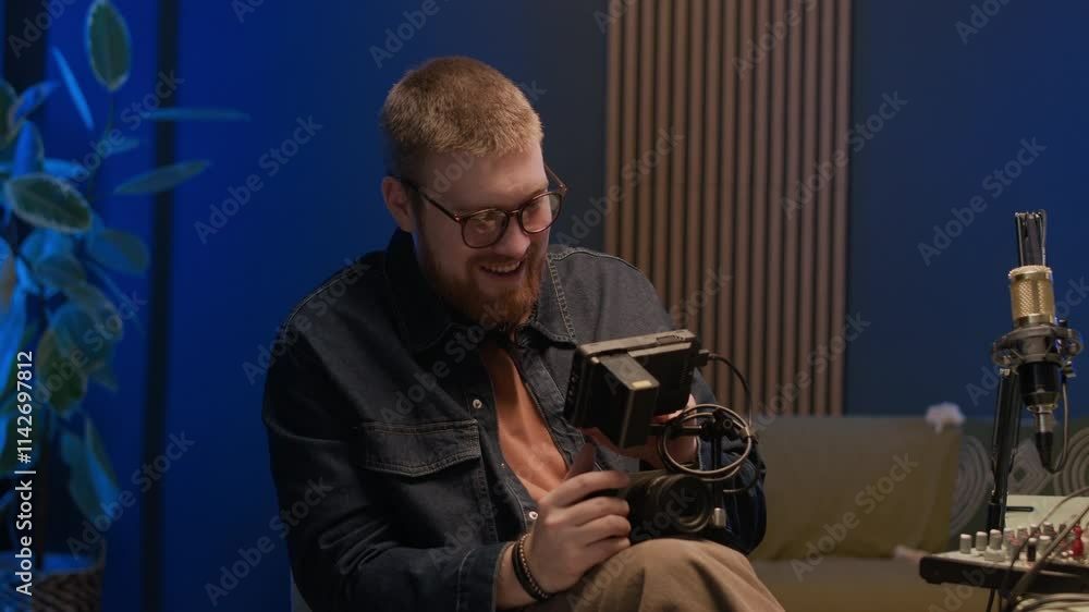 Medium shot of young smiling Caucasian man talking while setting up ...