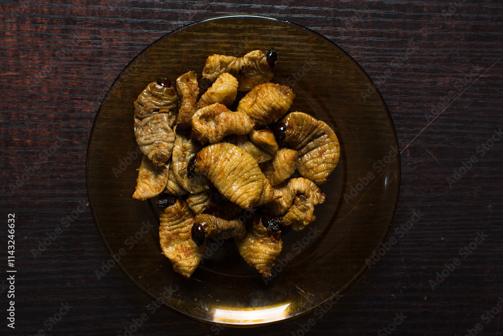 Overhead view of roasted sago worms on a brown plate, top view of palm ...