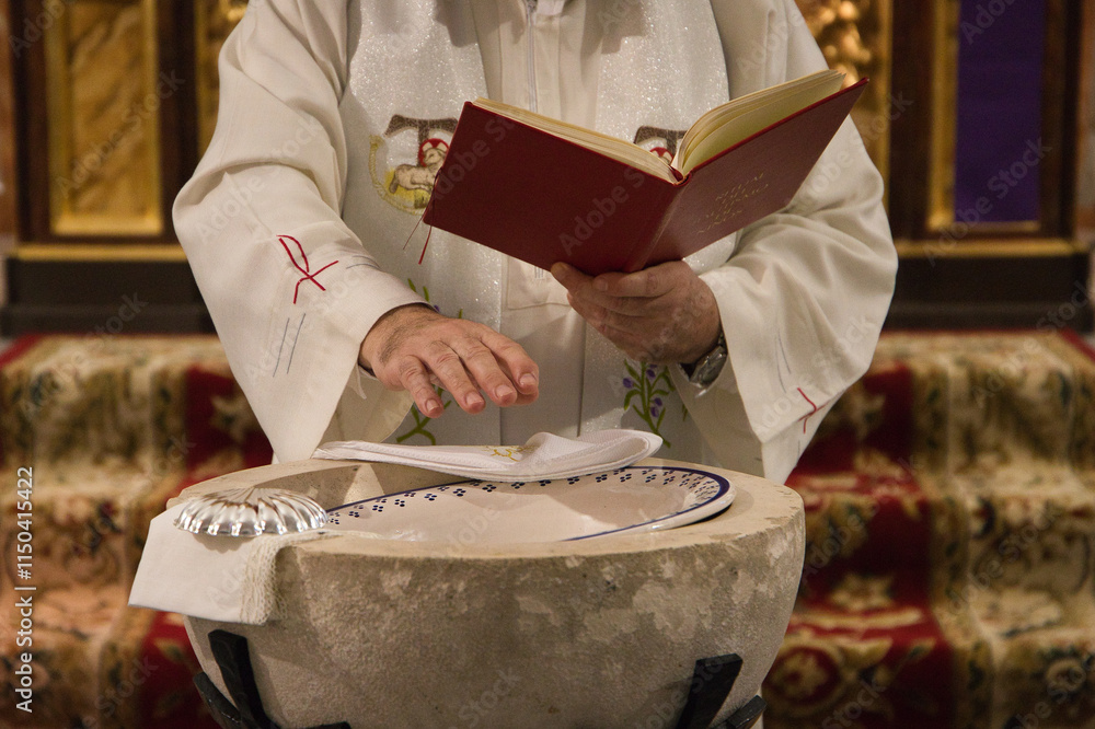 The priest blesses with his hands the water of the baptismal font to ...