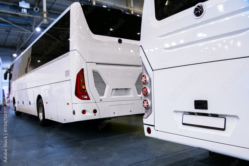 The image shows two white tourist buses parked next to each other. The ...