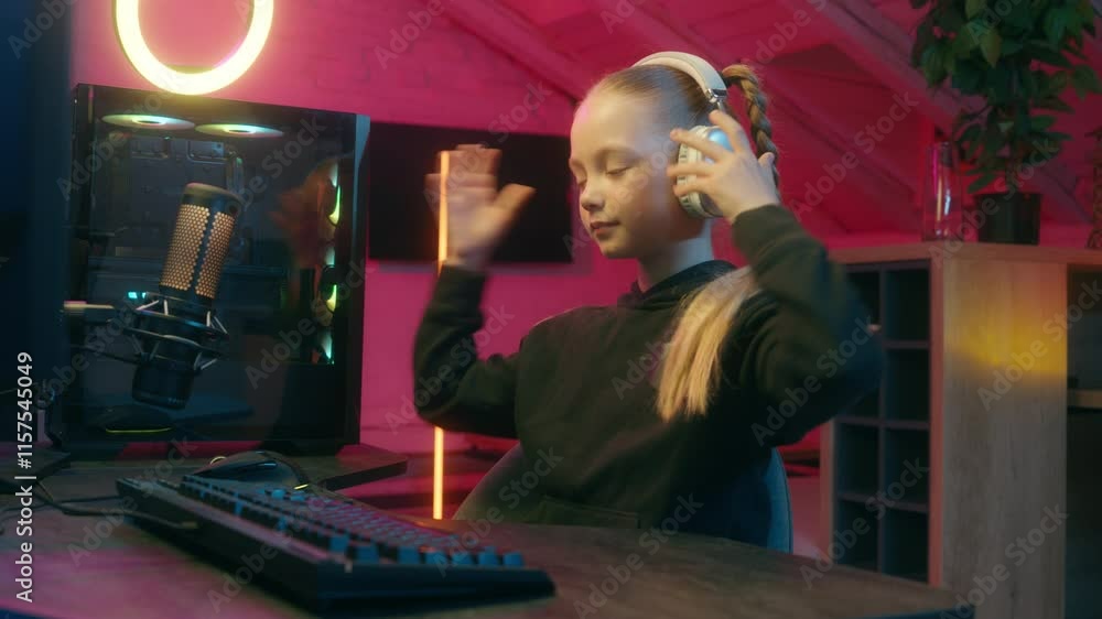 Teenager little girl gamer streamer put on headphones looking at camera ...