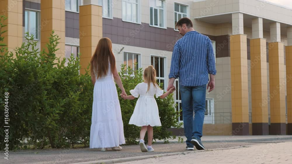 Mother and father take little daughter to school holding hands in city ...
