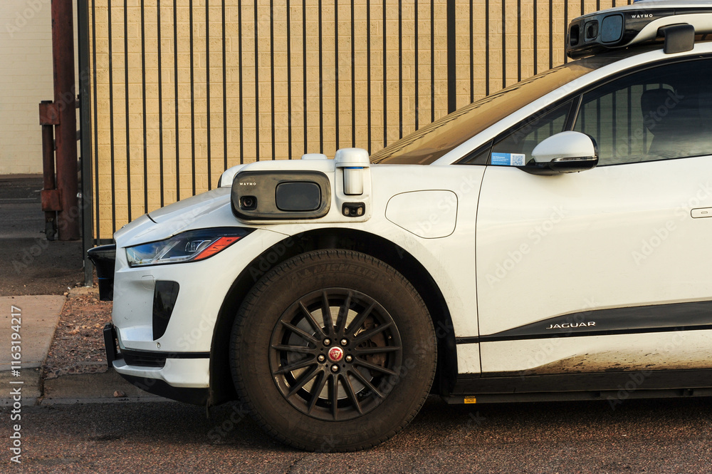 A partial front-end view of a white Jaguar Waymo self-driving vehicle ...