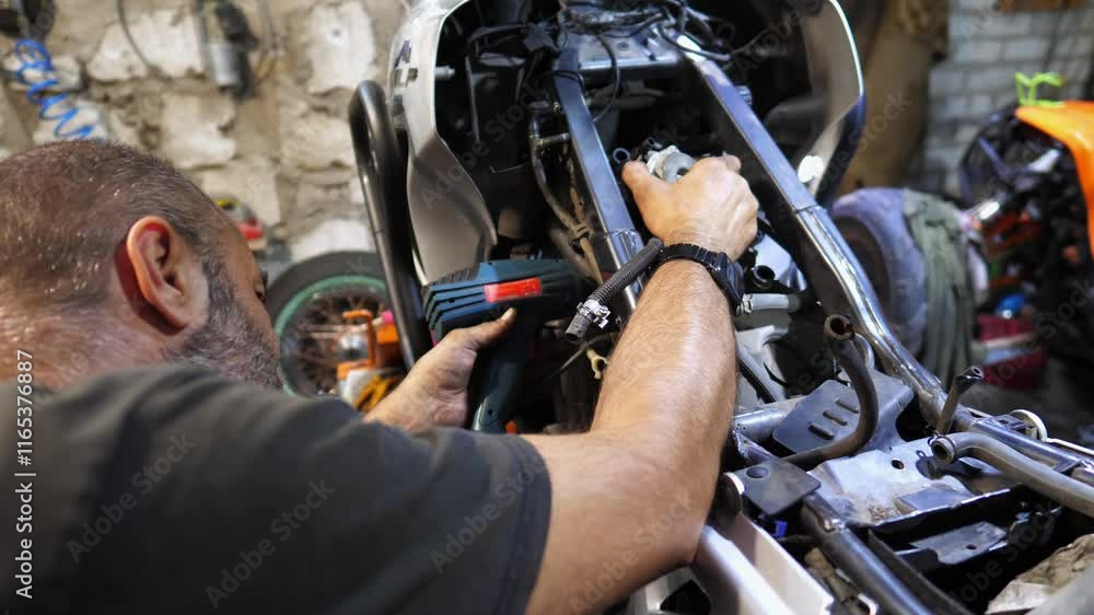 Professional mechanic repairing engine of motorcycle at workshop. Male ...