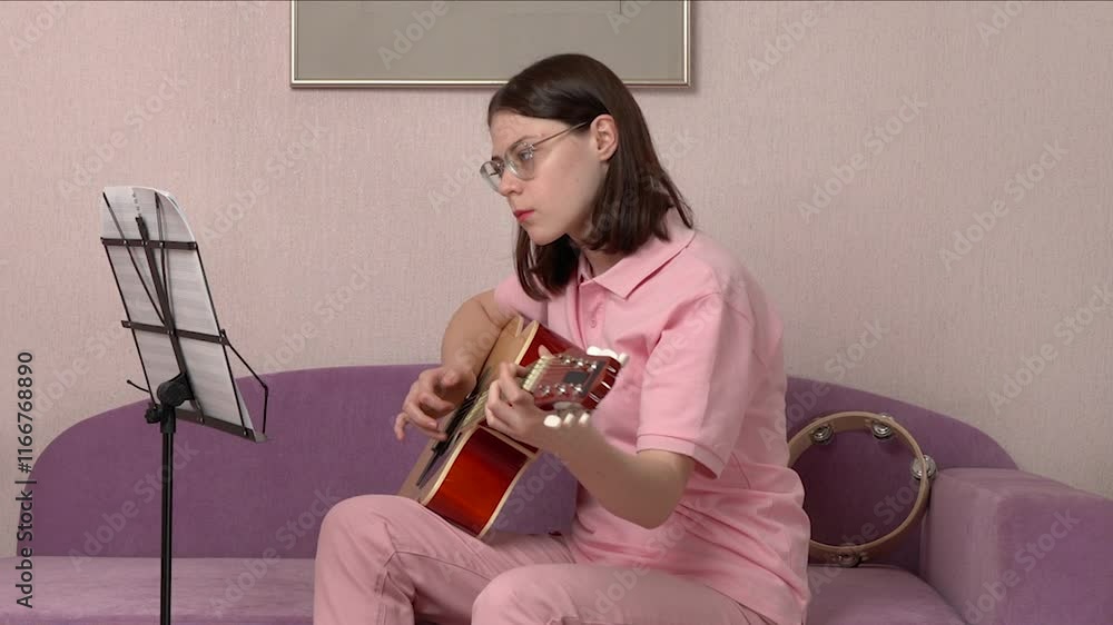 Woman with glasses is plucking six string acoustic guitar fingerstyle ...