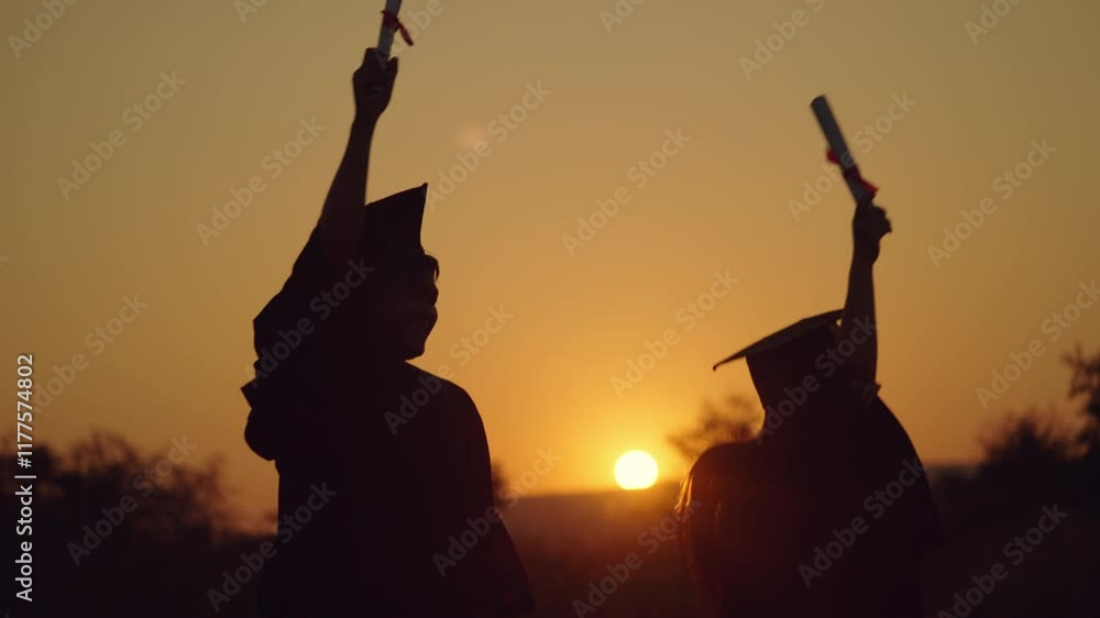 Two graduates are holding their graduation certificates in the air ...