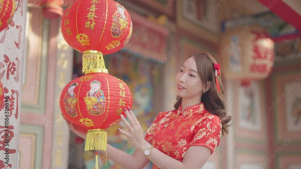 A woman wearing a red dress holding two red lanterns. The lanterns have ...