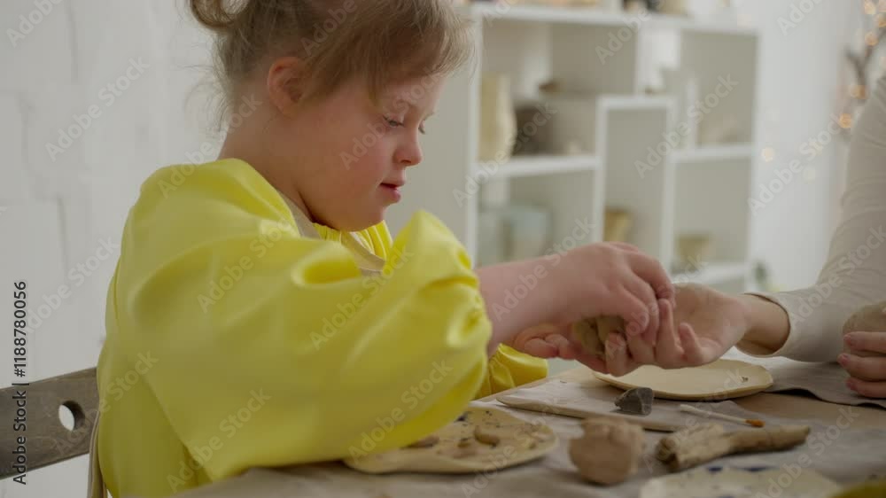 Young girl with Down syndrome, wearing yellow dress and apron, taking a ...