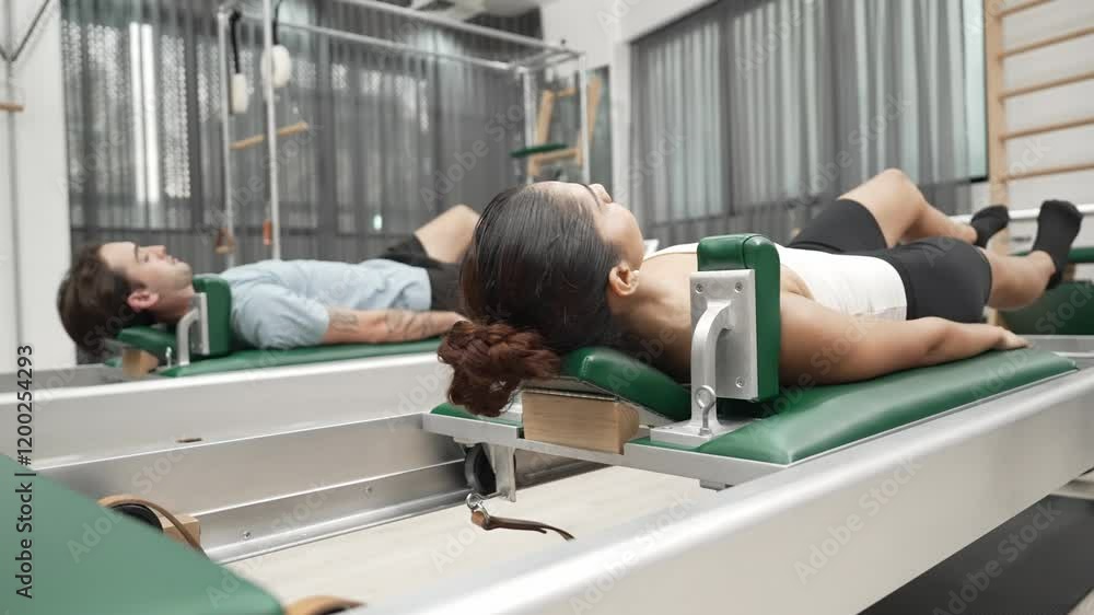 Couple practicing leg exercises on pilates reformer to strengthen core ...