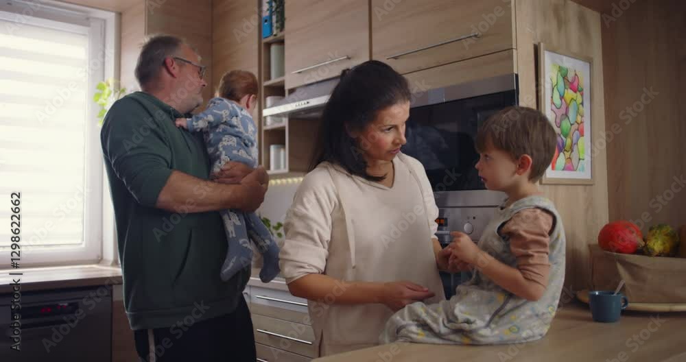 Family interaction in modern kitchen, mother comforting child sitting ...