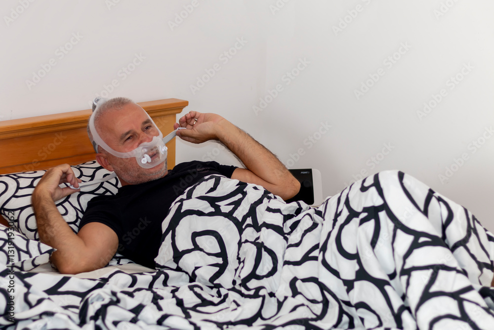Poster A mature man laying in bed holding CPAP mask with a smiling face ...